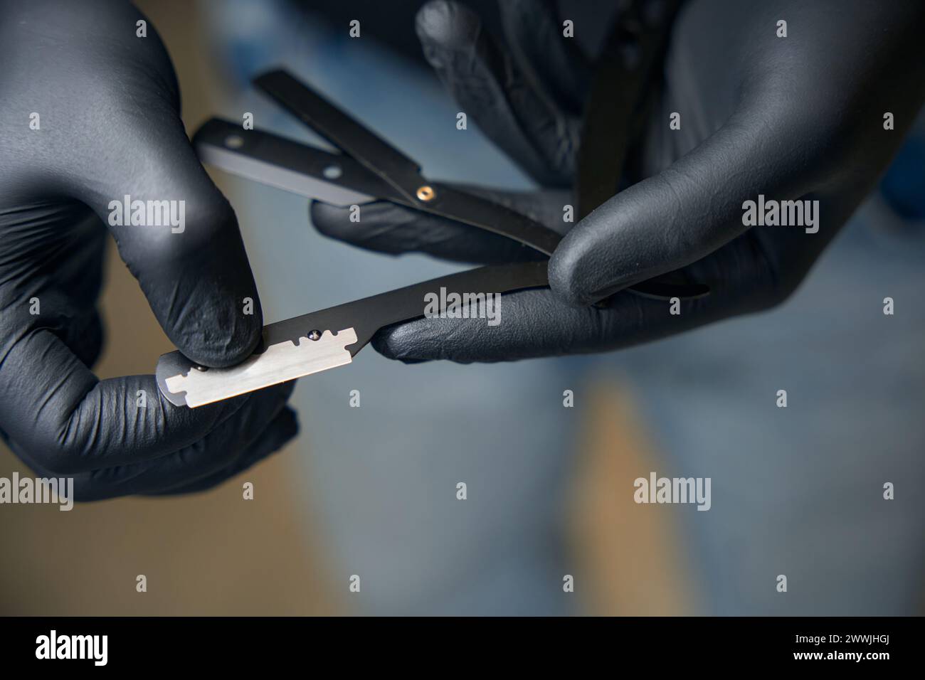 Barber in black gloves holding razor for shaving beards in barbershop ...