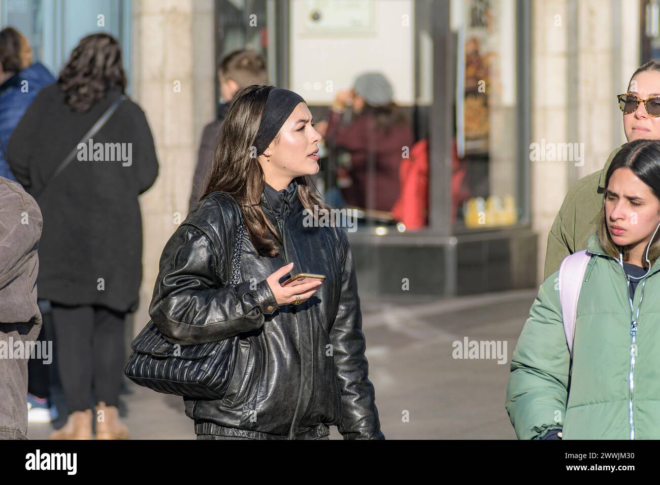 Street portrait of young happy stylish woman in black with mobile phone ...