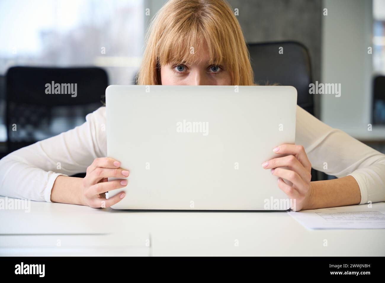 Shy woman hiding her face behind laptop Stock Photo - Alamy