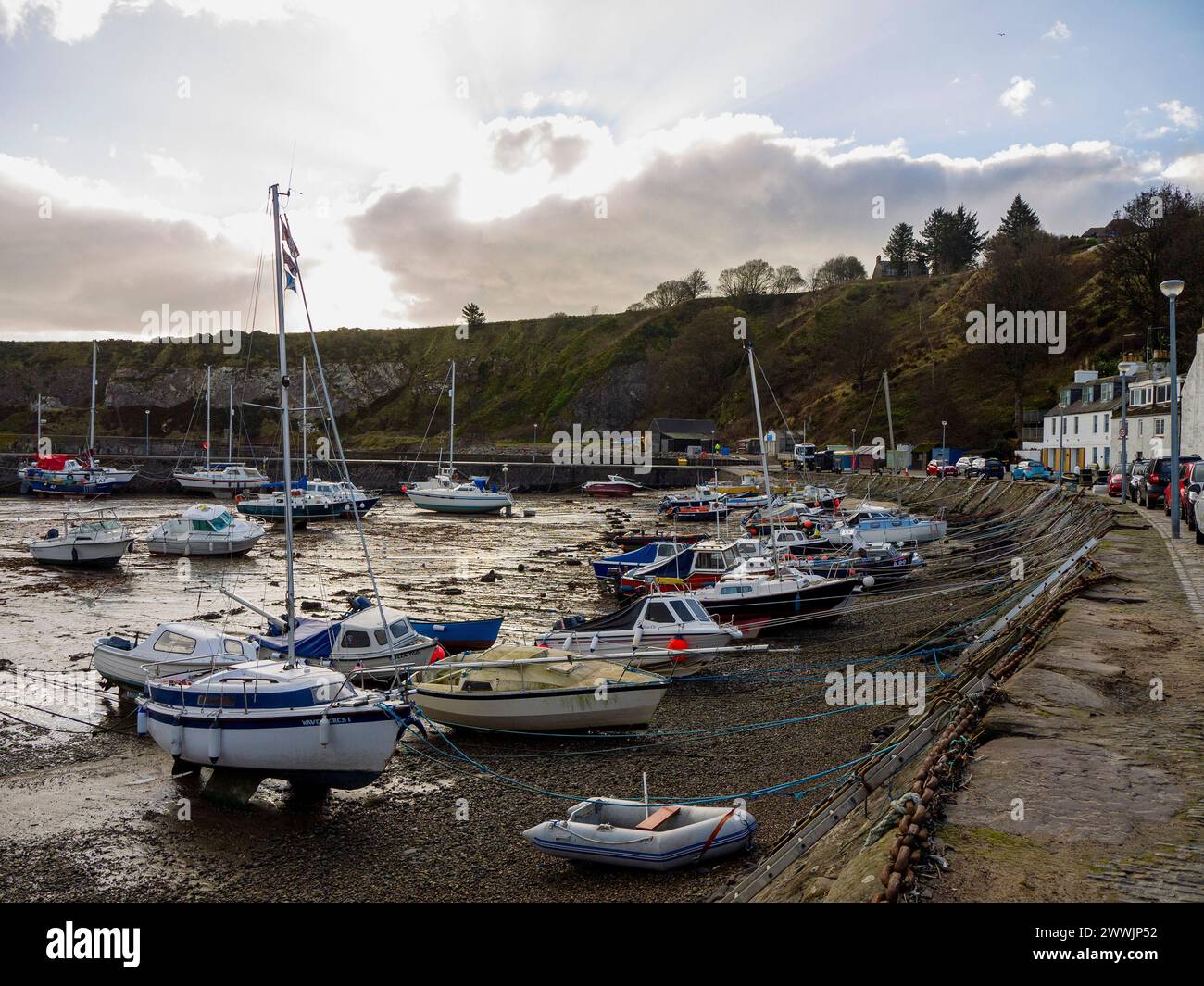 Tethered sailing and fishing boats along the shingle beach of ...