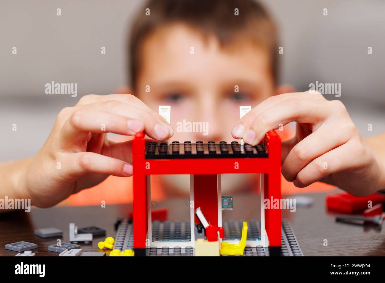 Child building a red toy structure with blocks on a table Stock Photo ...