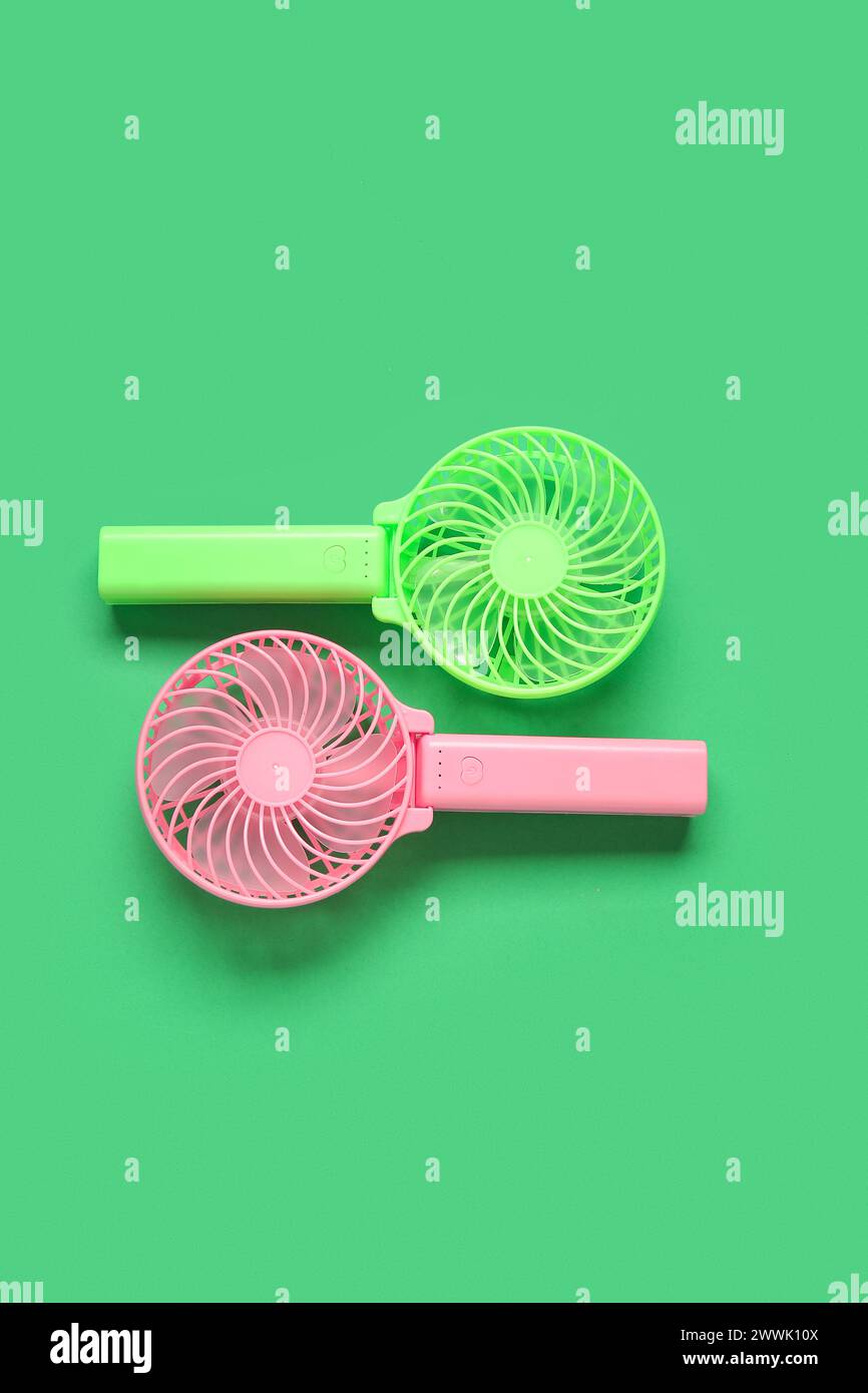 Different manual fans on green background Stock Photo - Alamy