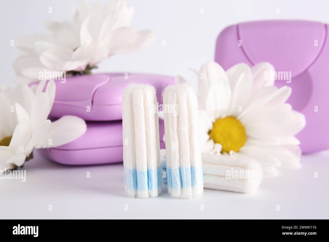 Menstrual tampons, storage boxes and chamomile flowers on white ...