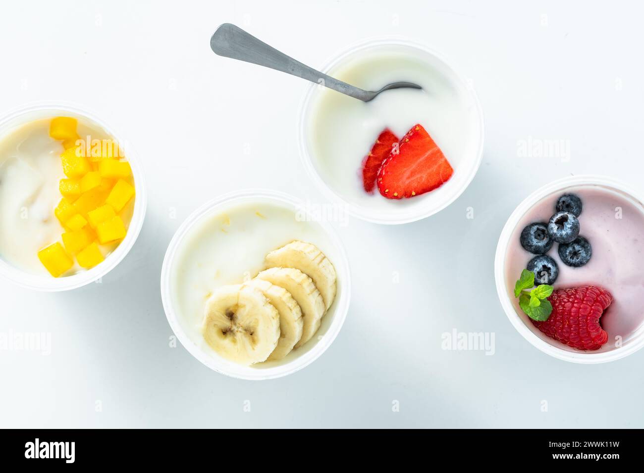 assortment of different yogurts with berries, fruits, mango and banana ...