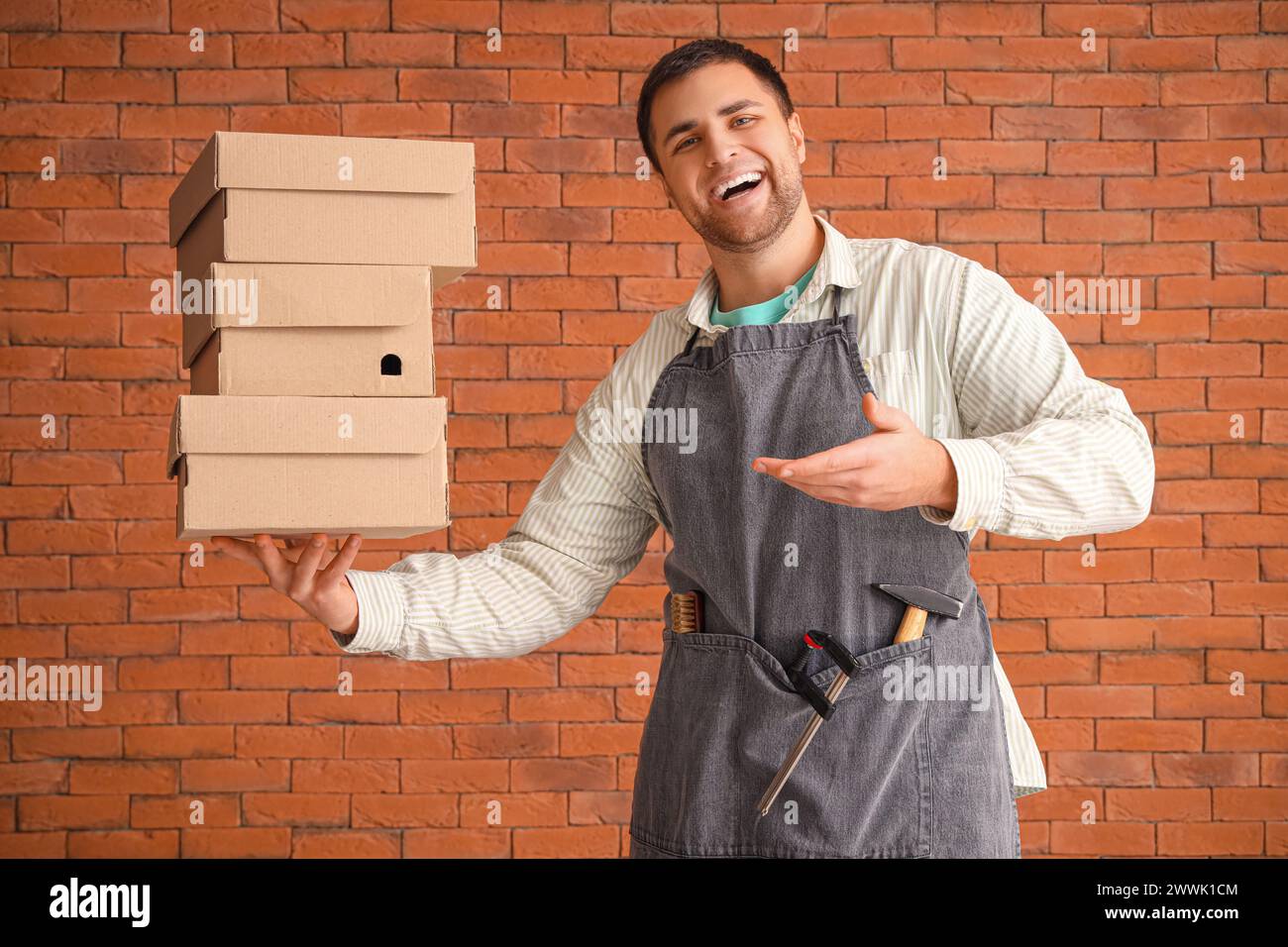 Male shoemaker with shoe boxes on brick background Stock Photo - Alamy