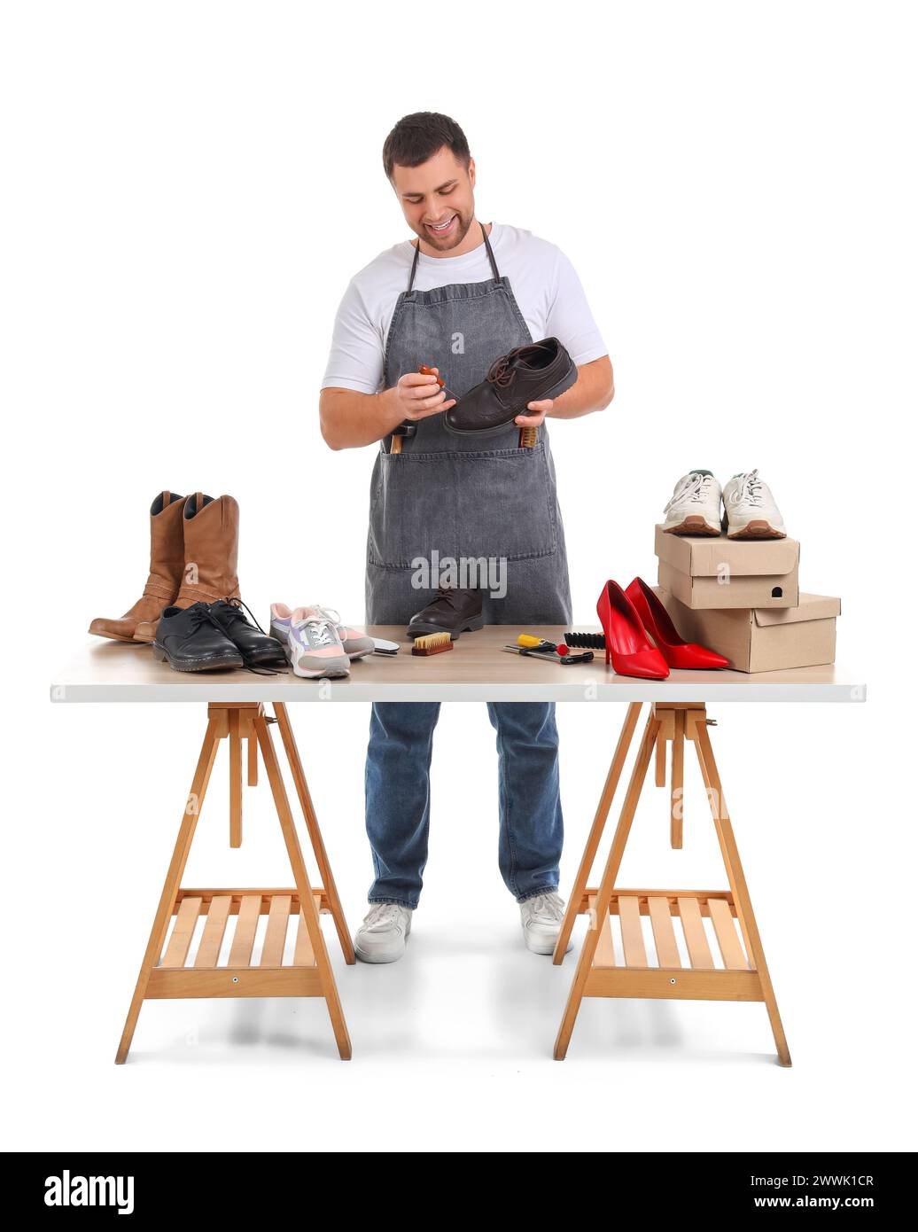 Male shoemaker with shoes at table on white background Stock Photo - Alamy
