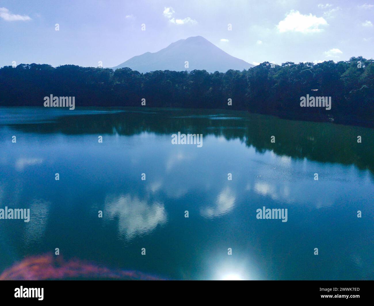 An aerial view of a clear blue lake with a dramatic, clouds capped ...