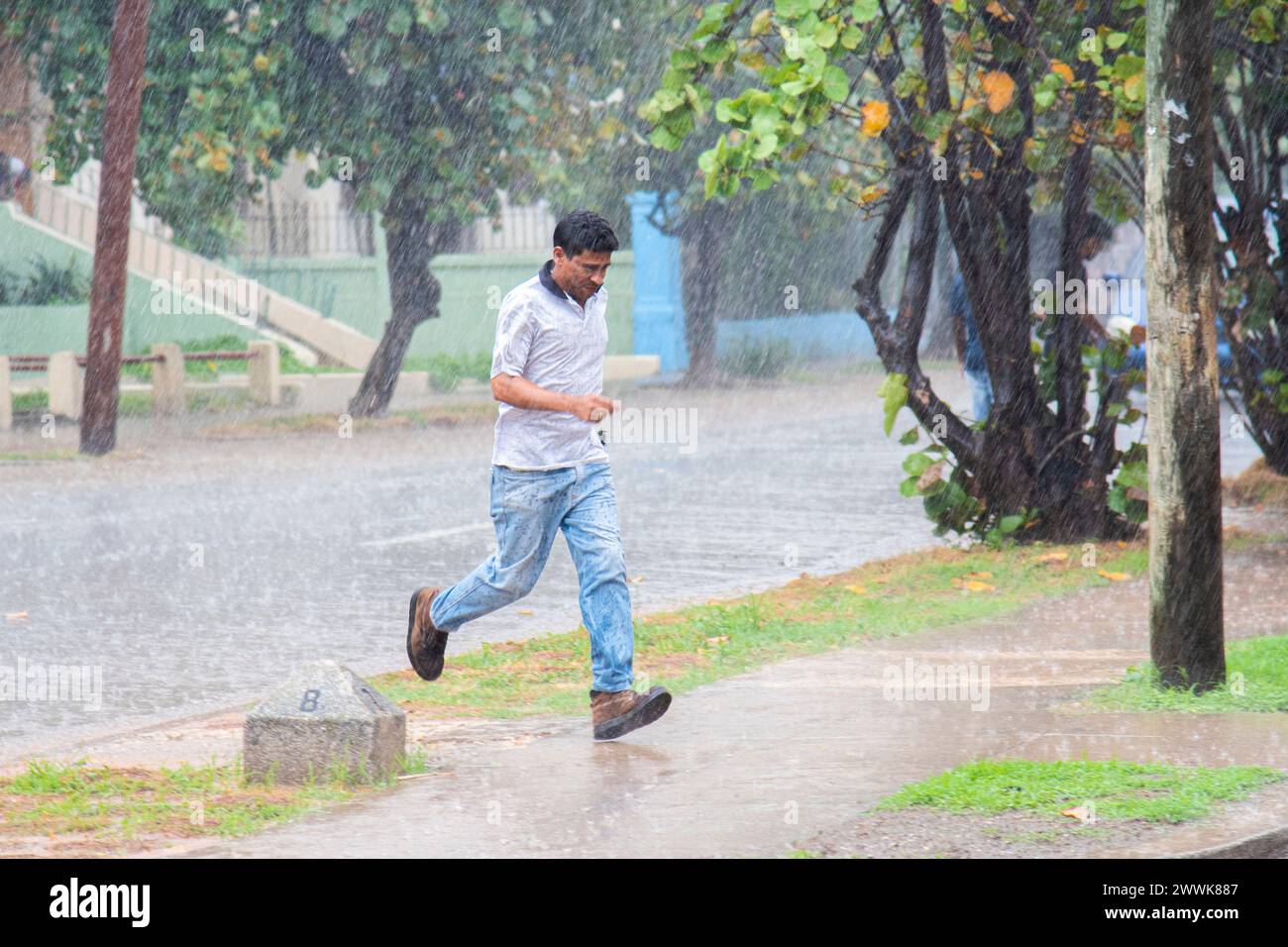 A man runs through a street in Havana, Cuba in the middle of a rain ...