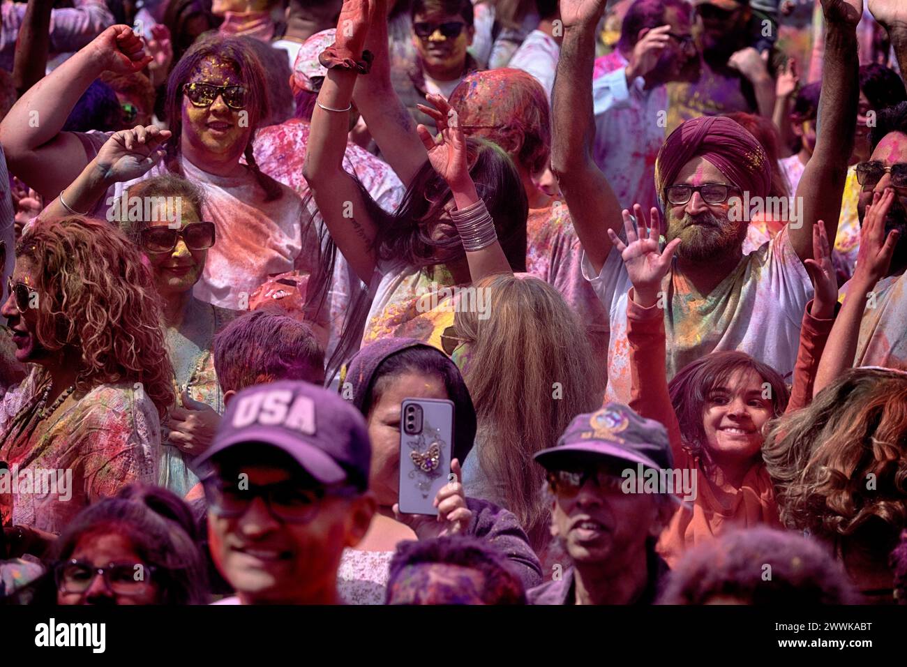 Celebrants covered in colored powder dance and sing during Holi, the ...