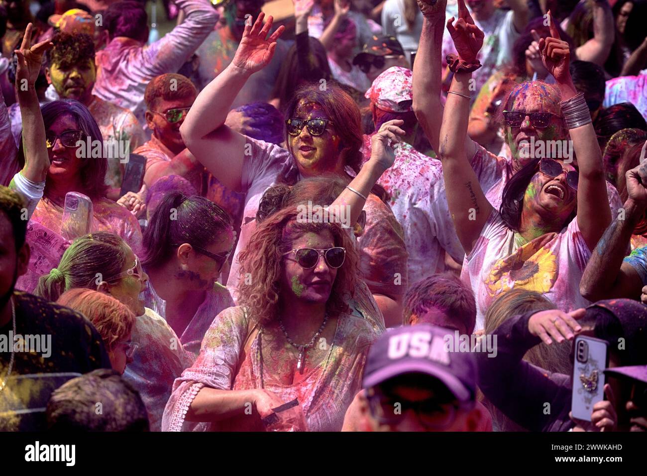 Celebrants covered in colored powder dance and sing during Holi, the ...