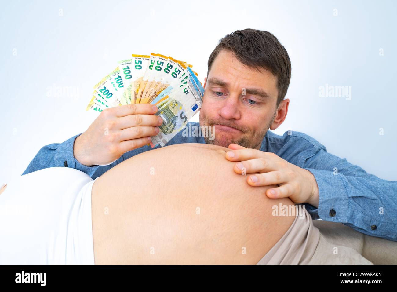 Description: Expectant father with stack of banknotes in hand ...