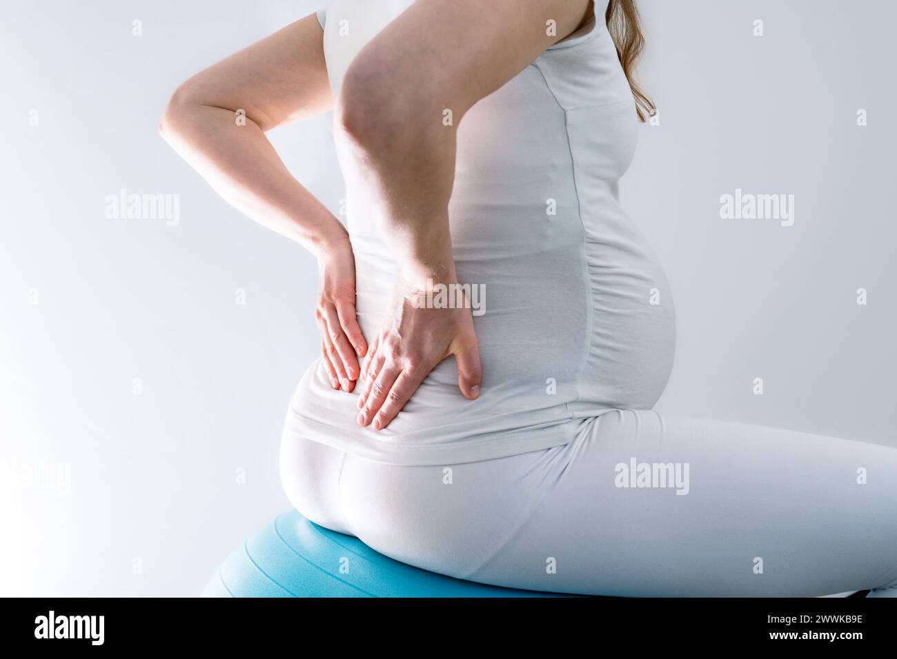 Description: Pregnant woman with baby bump feels back pain and holds ...