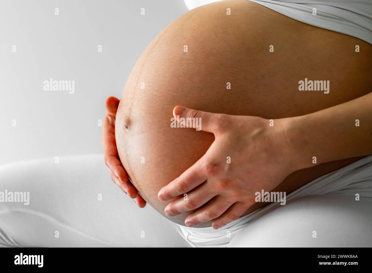 Description: Woman sitting on an exercise ball and gently holding her ...