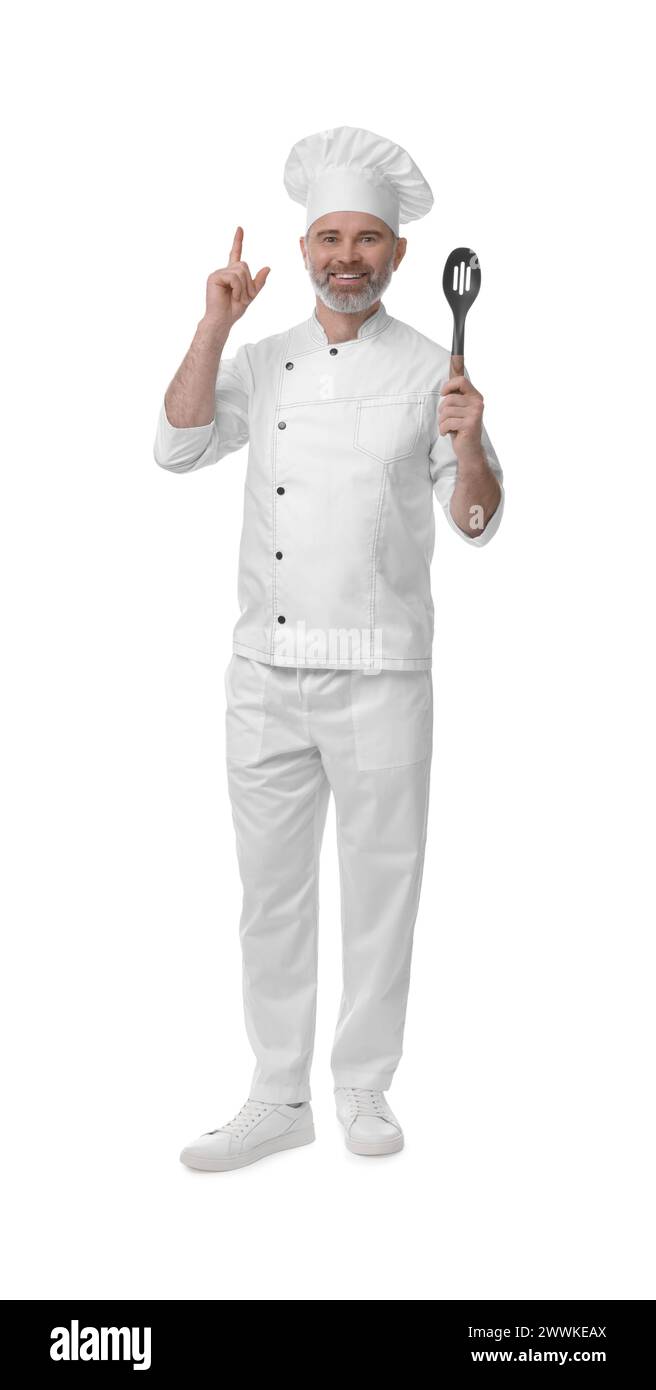 Happy chef in uniform with spoon pointing at something on white ...