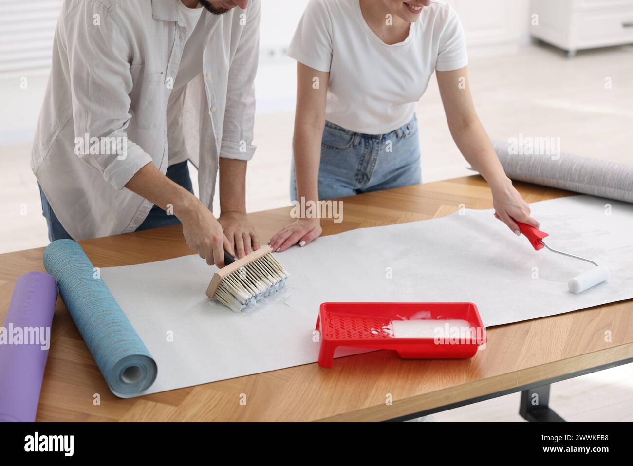 Woman applying wallpaper glue on a wallpaper with a brush hi-res stock ...