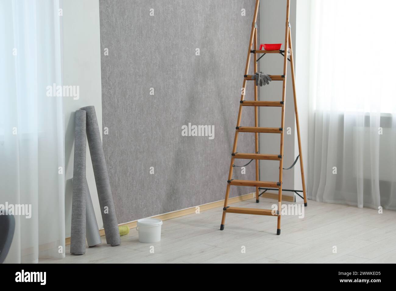 Wallpaper rolls, bucket with glue and wooden ladder in room Stock Photo ...