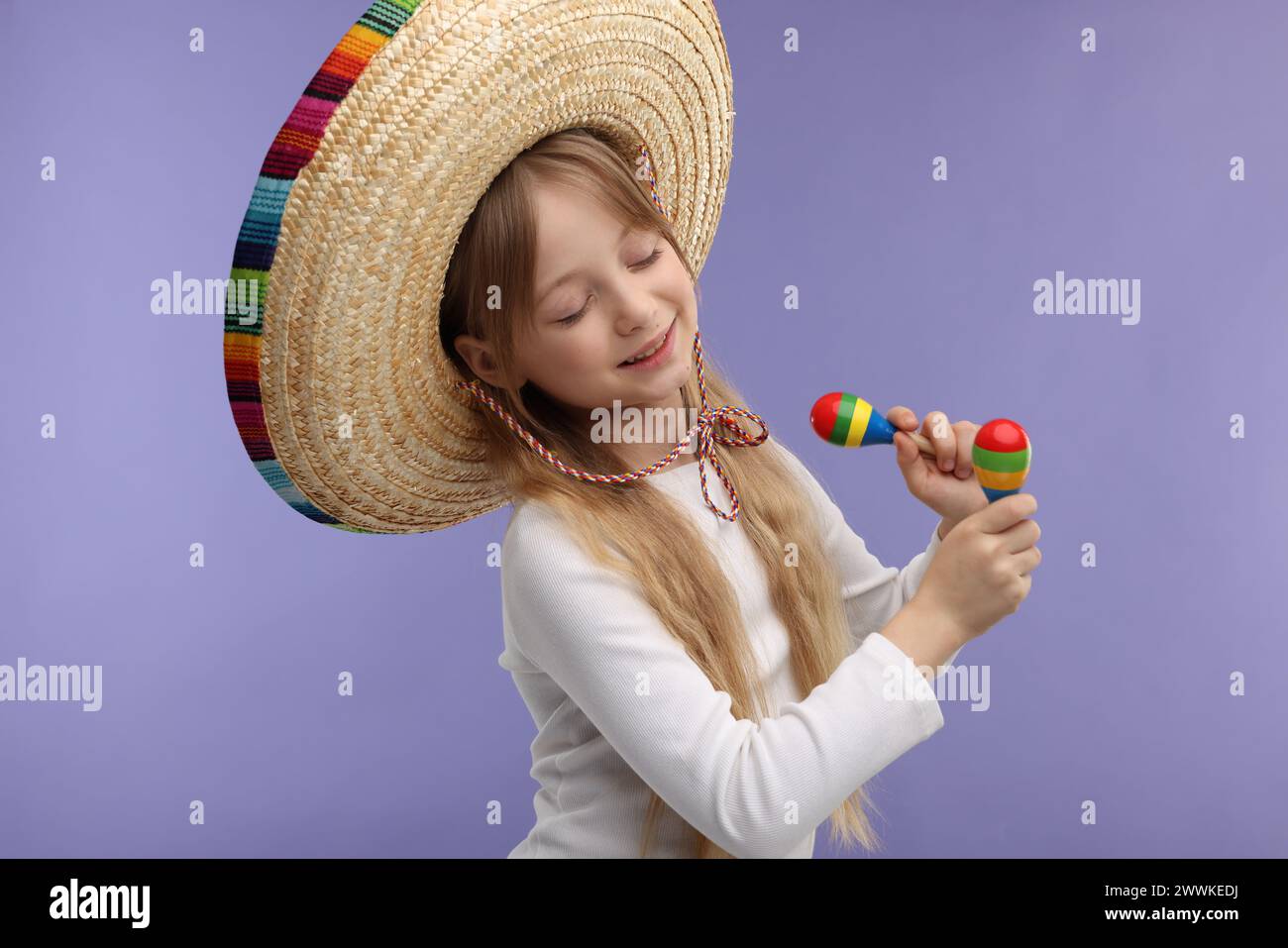 Cute girl in Mexican sombrero hat dancing with maracas on purple ...
