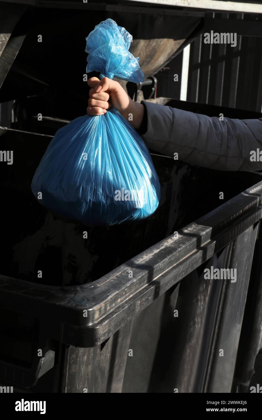 Woman throwing trash bag full of garbage in bin outdoors, closeup Stock ...