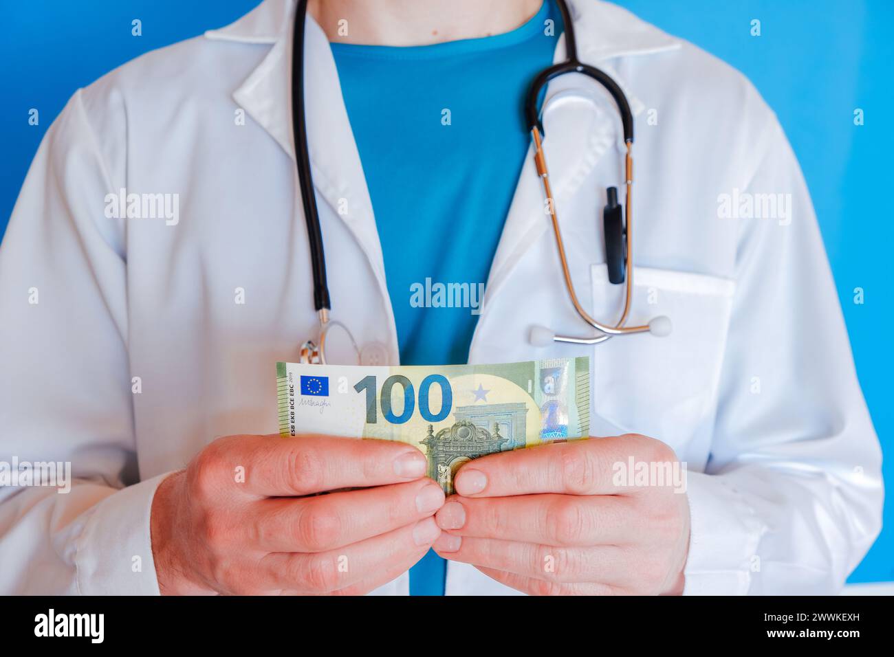 Paid medicine. doctor in a medical gown holds euro bills in his hand ...