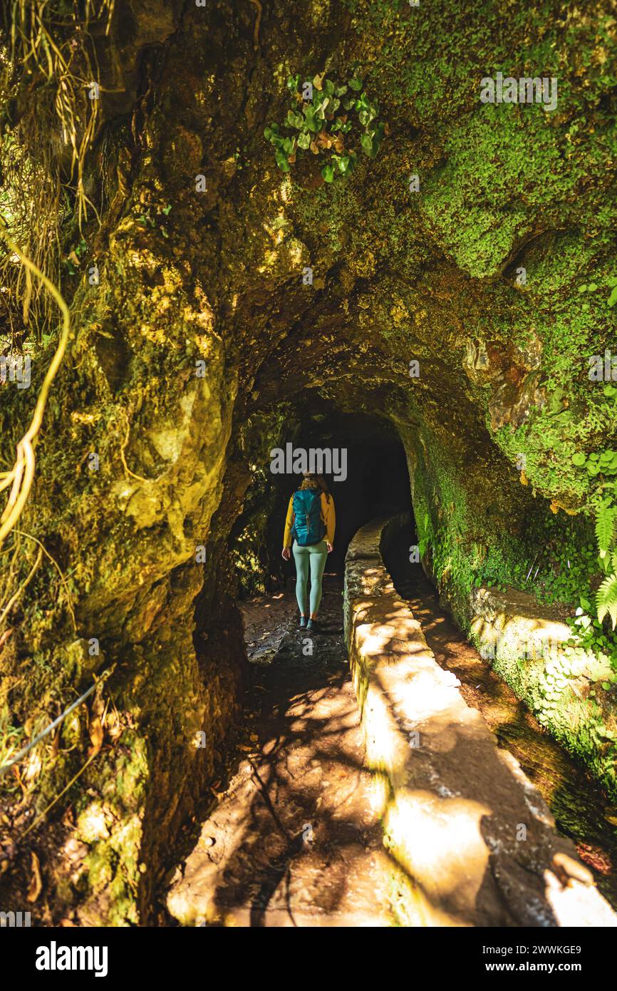 Description: Tourist woman exiting a tunnel along an overgrown jungle ...