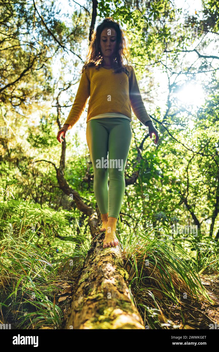 Description: Barefoot woman balancing on a tree trunk in beautiful ...