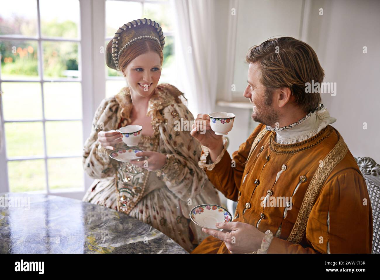 King, queen and couple with tea in castle, smile and conversation in ...