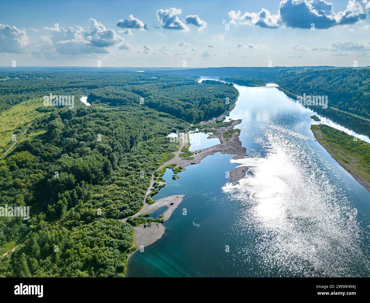 flat river with a branched channel and rocky pebble banks overgrown ...