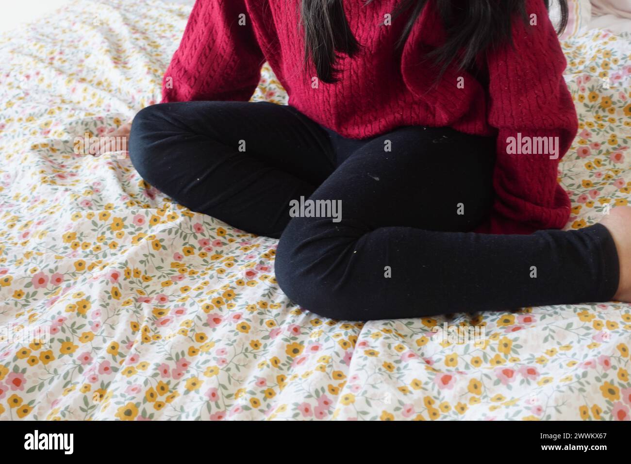 child sitting W posture on the bed Stock Photo - Alamy