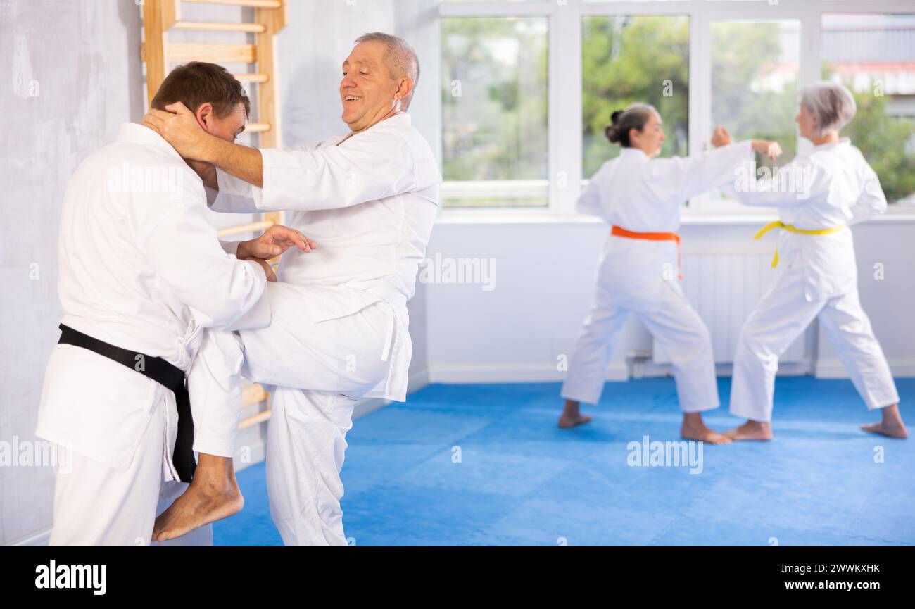 Old man attendee of karate classes fighting with his opponent in sports ...