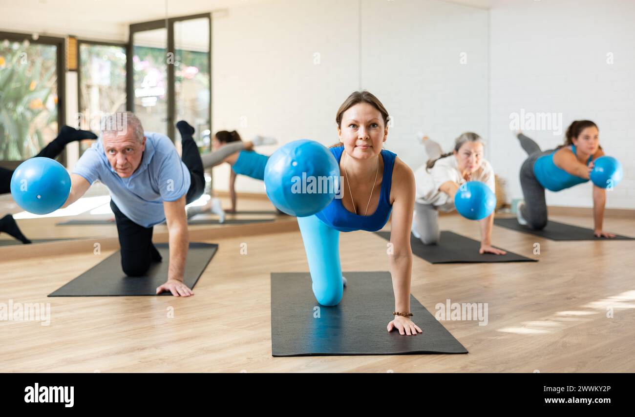 People of different ages stretching leg and arm, holding mini ball in ...