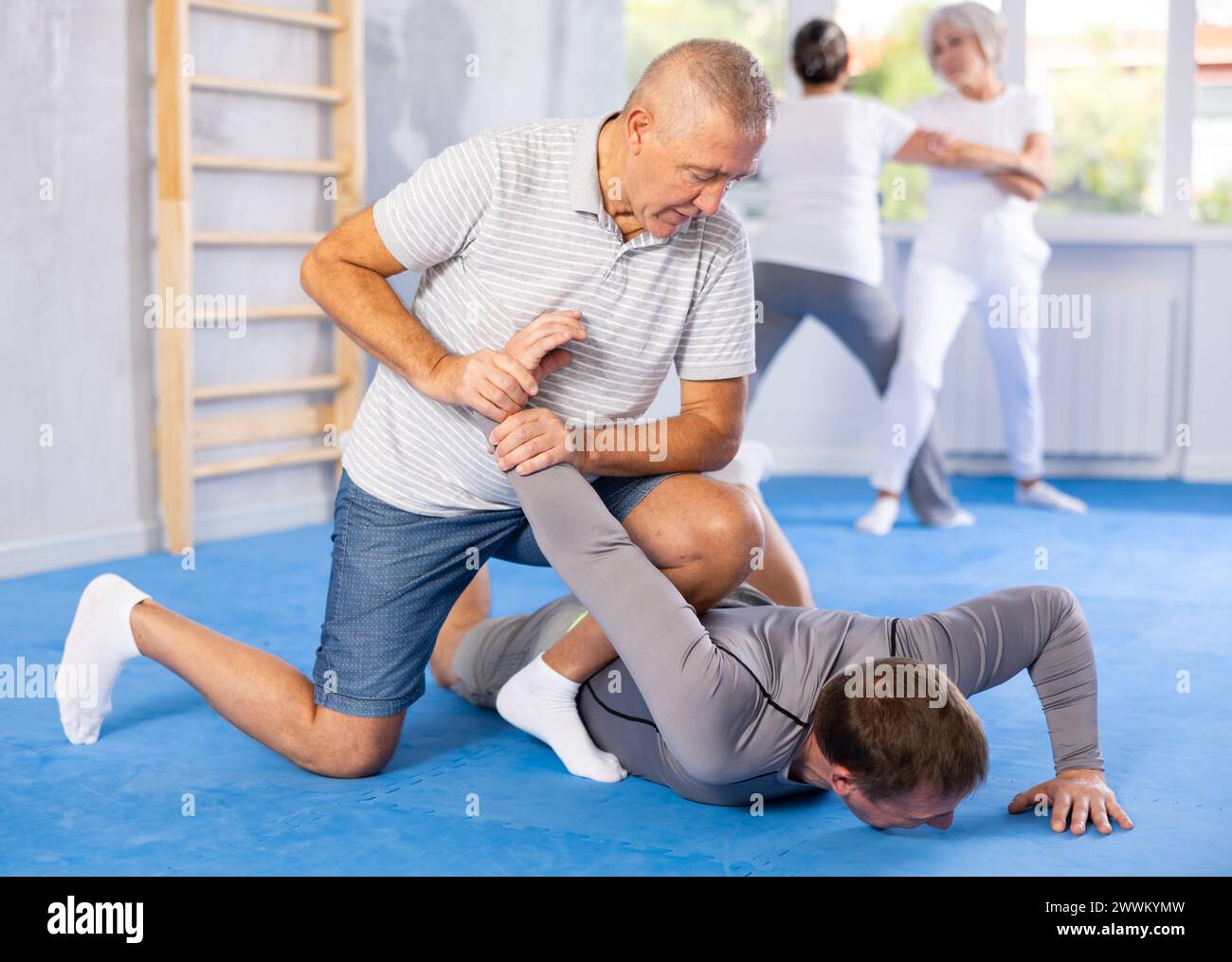 Old man twisting her opponent's arm during self-defense classes Stock ...