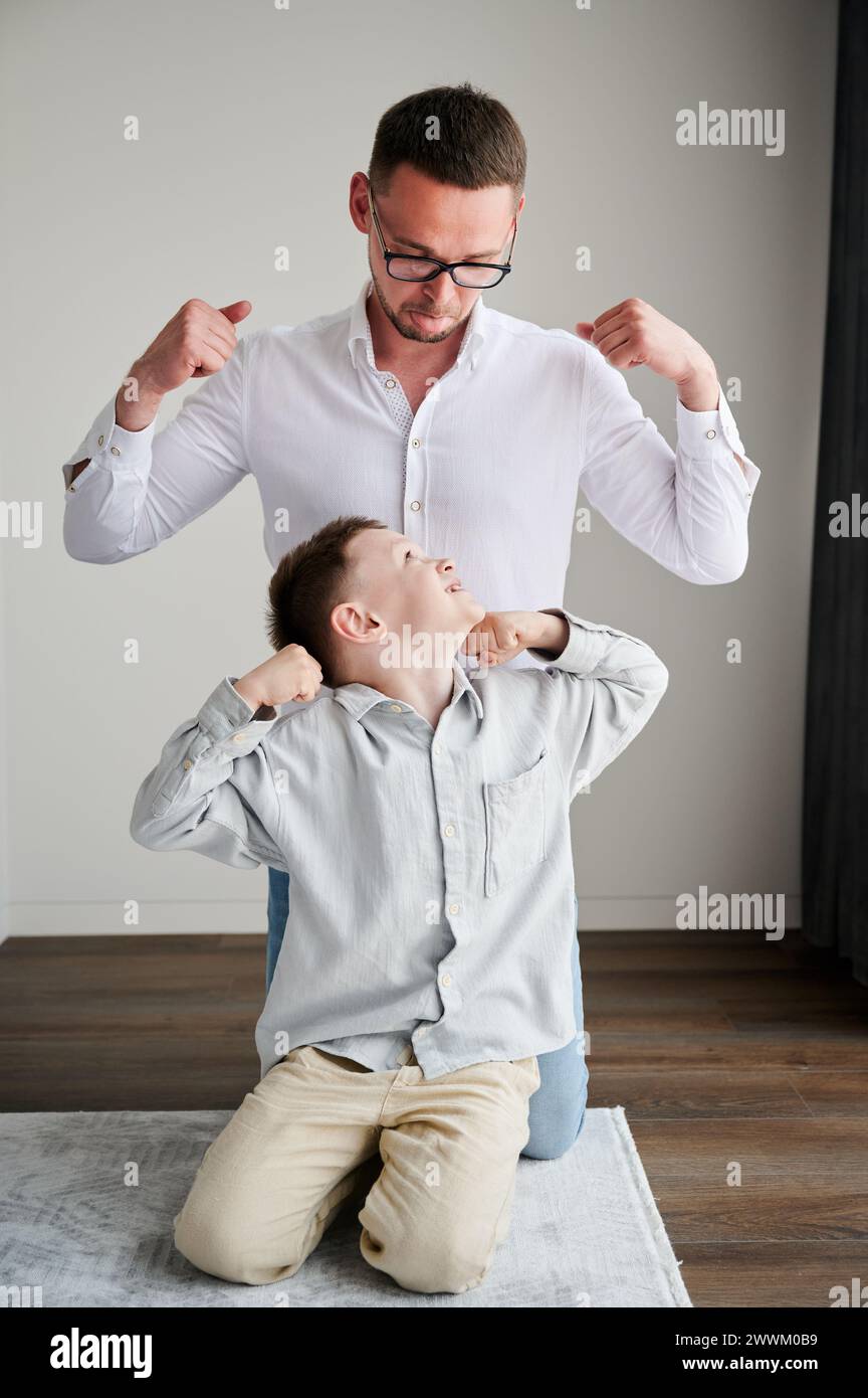 Young father playing with his curious son. Funny kid showing muscles to ...
