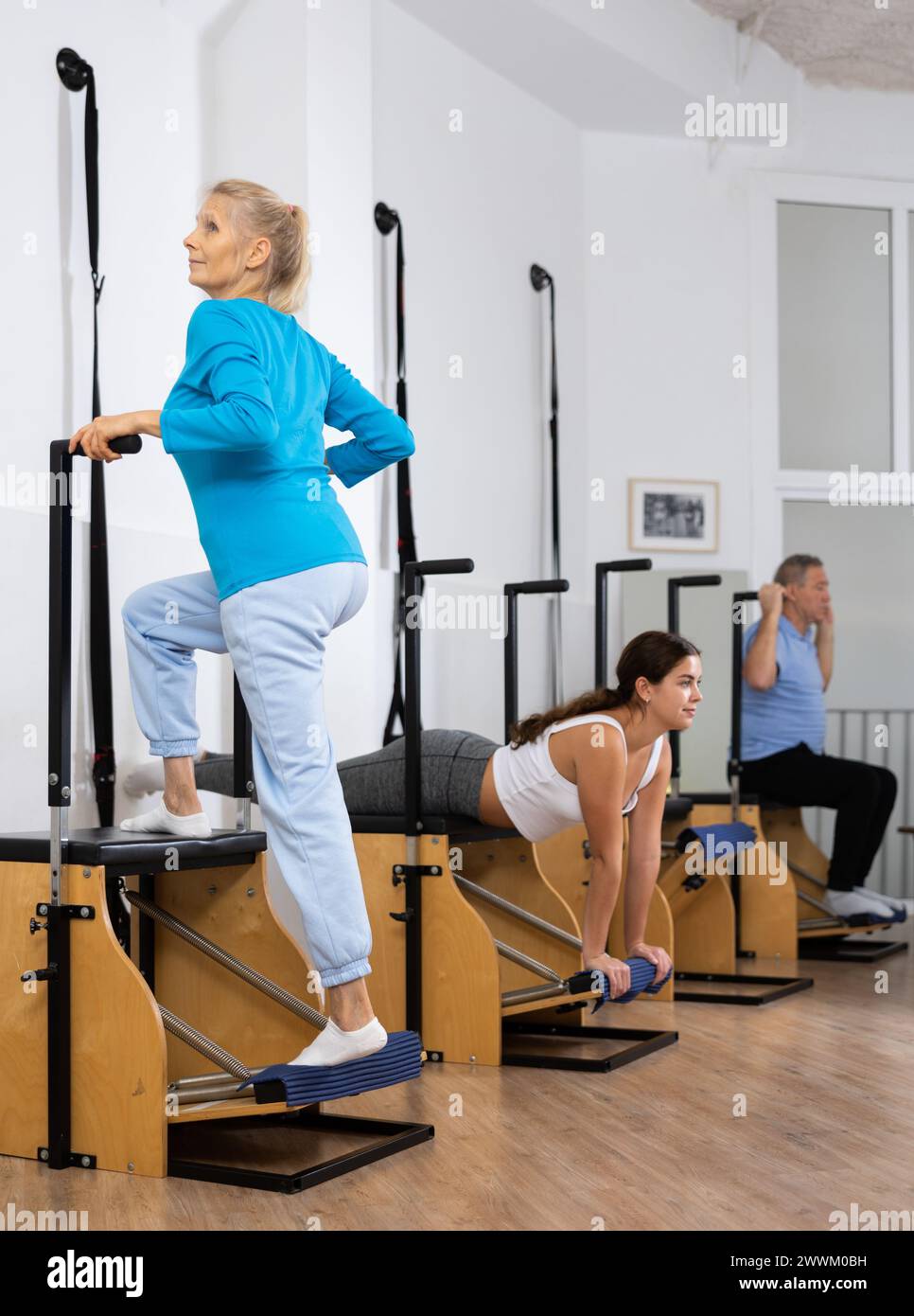 Relaxed aged woman wearing sportswear doing standing exercises on ...