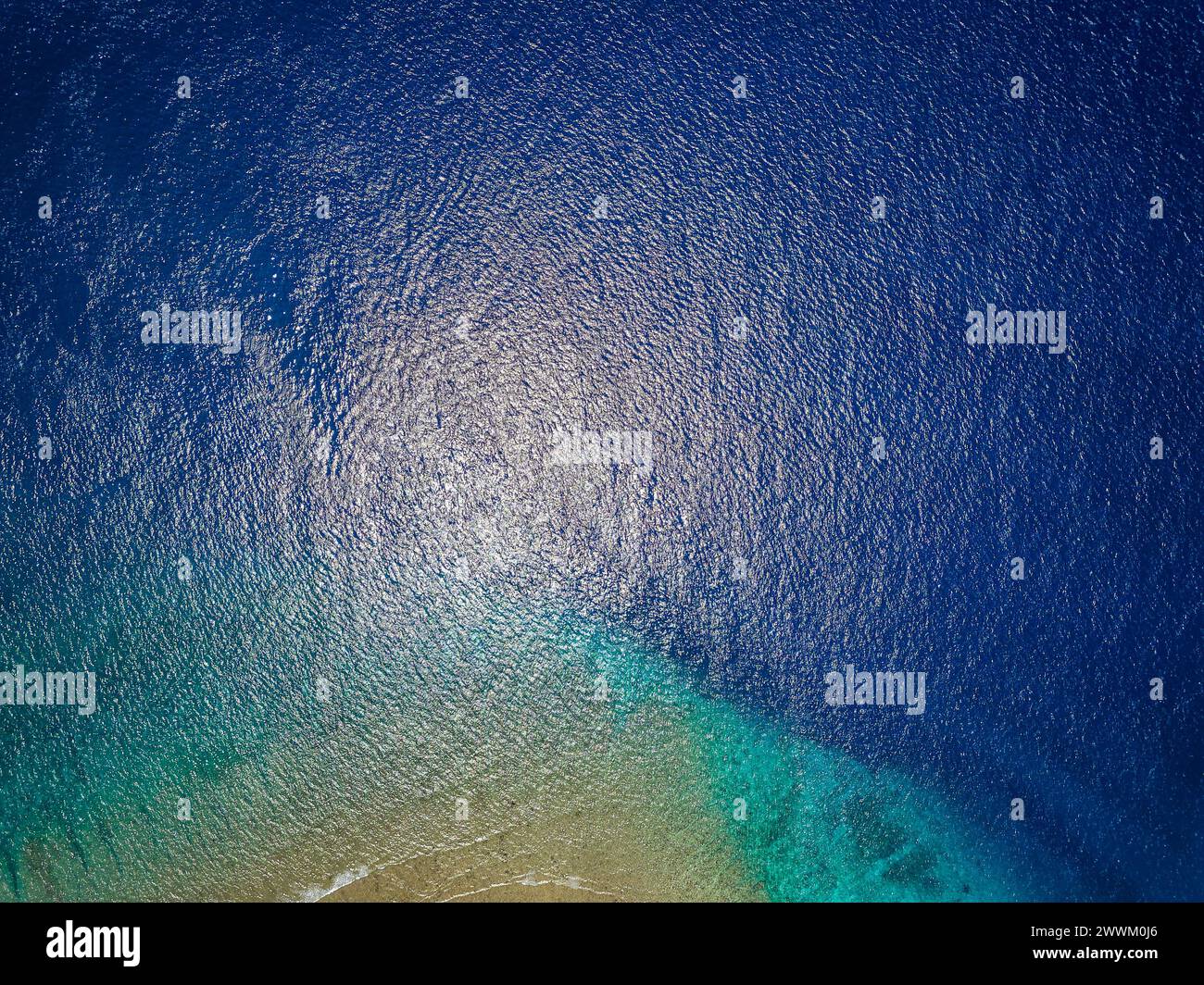 Top down aerial view of blue water and a tropical coral reef in a warm ...