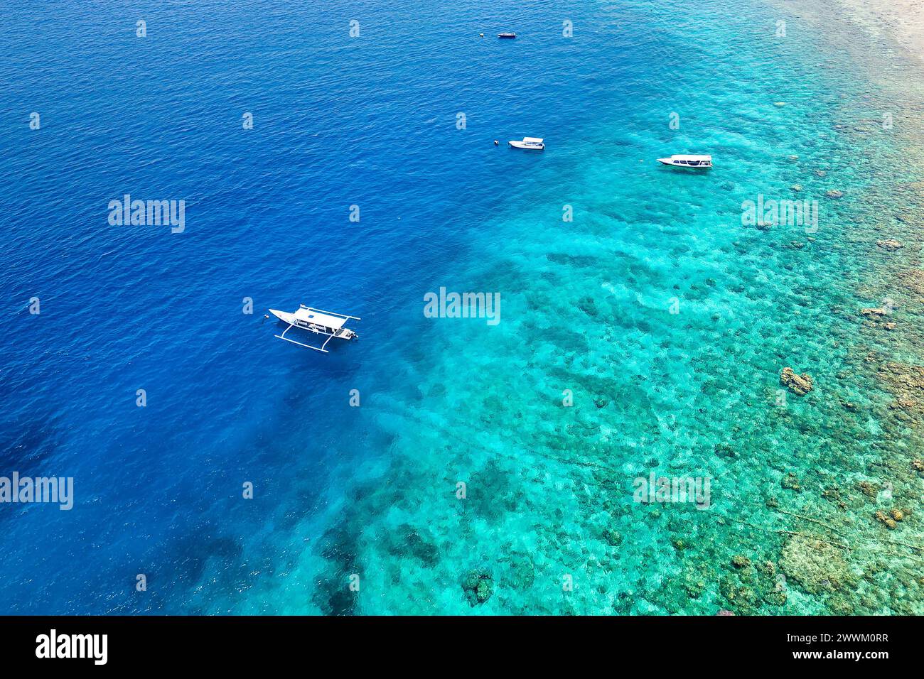 Tourist boats over the wall of a fringing coral reef in Indonesia Stock ...