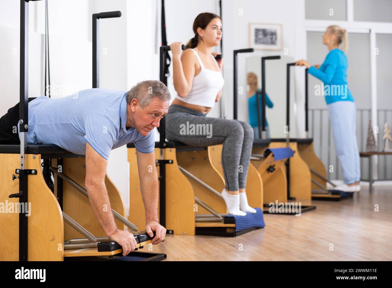 Focused man and women of different ages performing stretching exercises ...