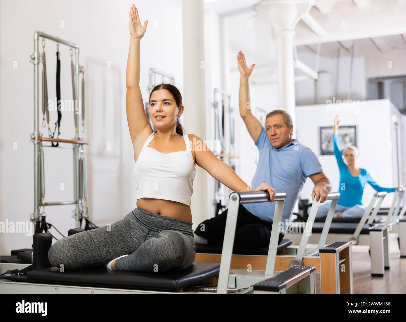 Active young woman stretching upper body practicing Pilates exercise in ...