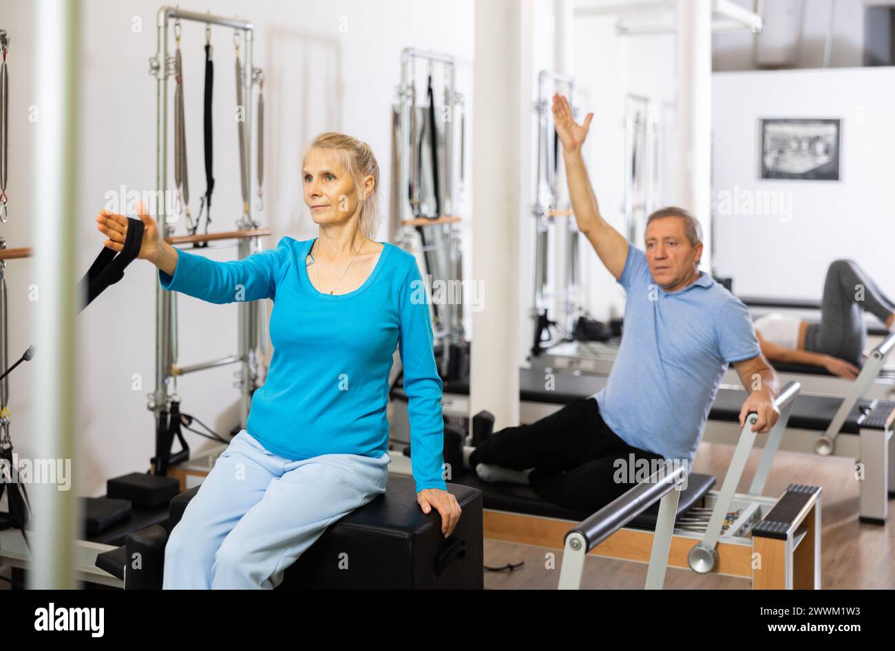Mature couple using bed of Pilates reformer bed equipment while ...