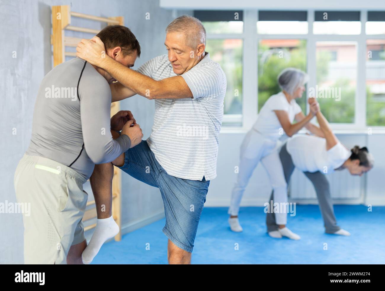 Senior man in pair with middle-aged coach train Krav Maga and self ...