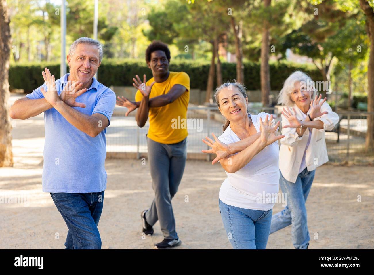 Positive mature women and men practicing vigorous dance movements in ...
