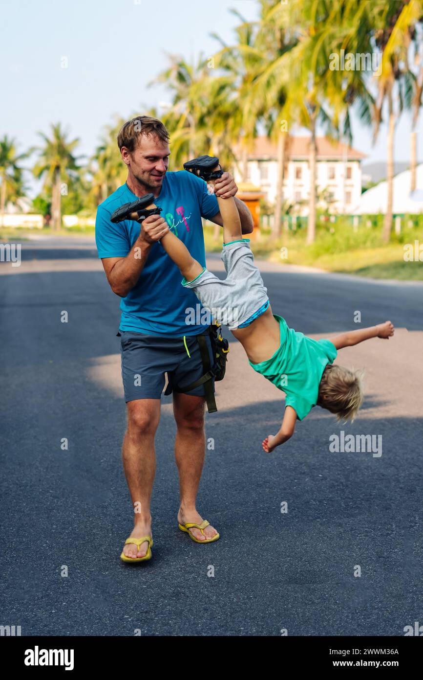 Father son have fun. Man holds child's leg upside down head. Joy ...