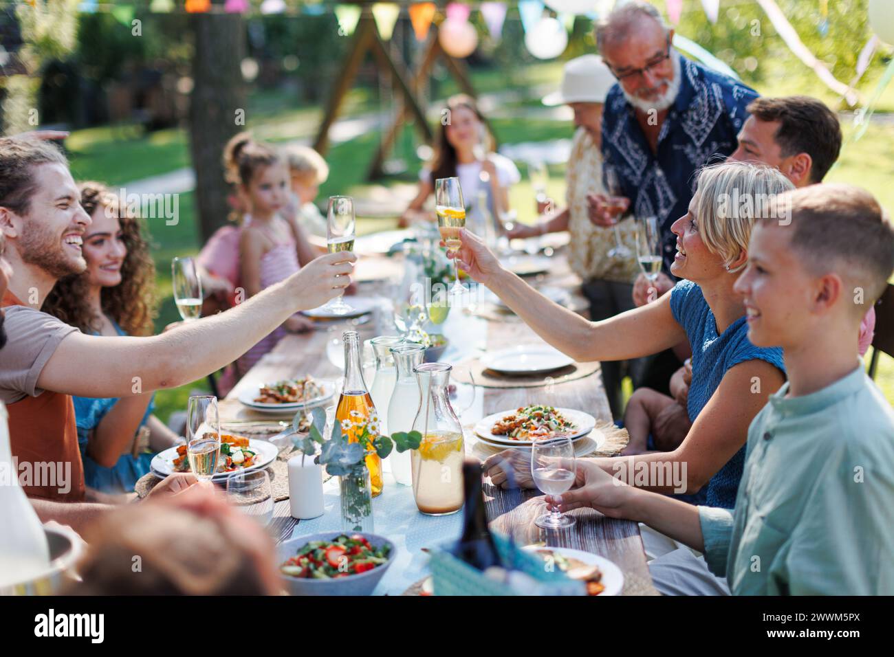 Family clinking glasses at summer garden party. Celebratory toast at ...