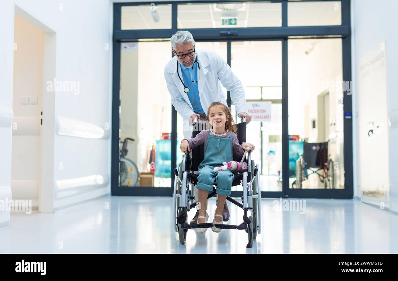 Friendly pediatrician pushing little patient in wheelchair. Cute ...
