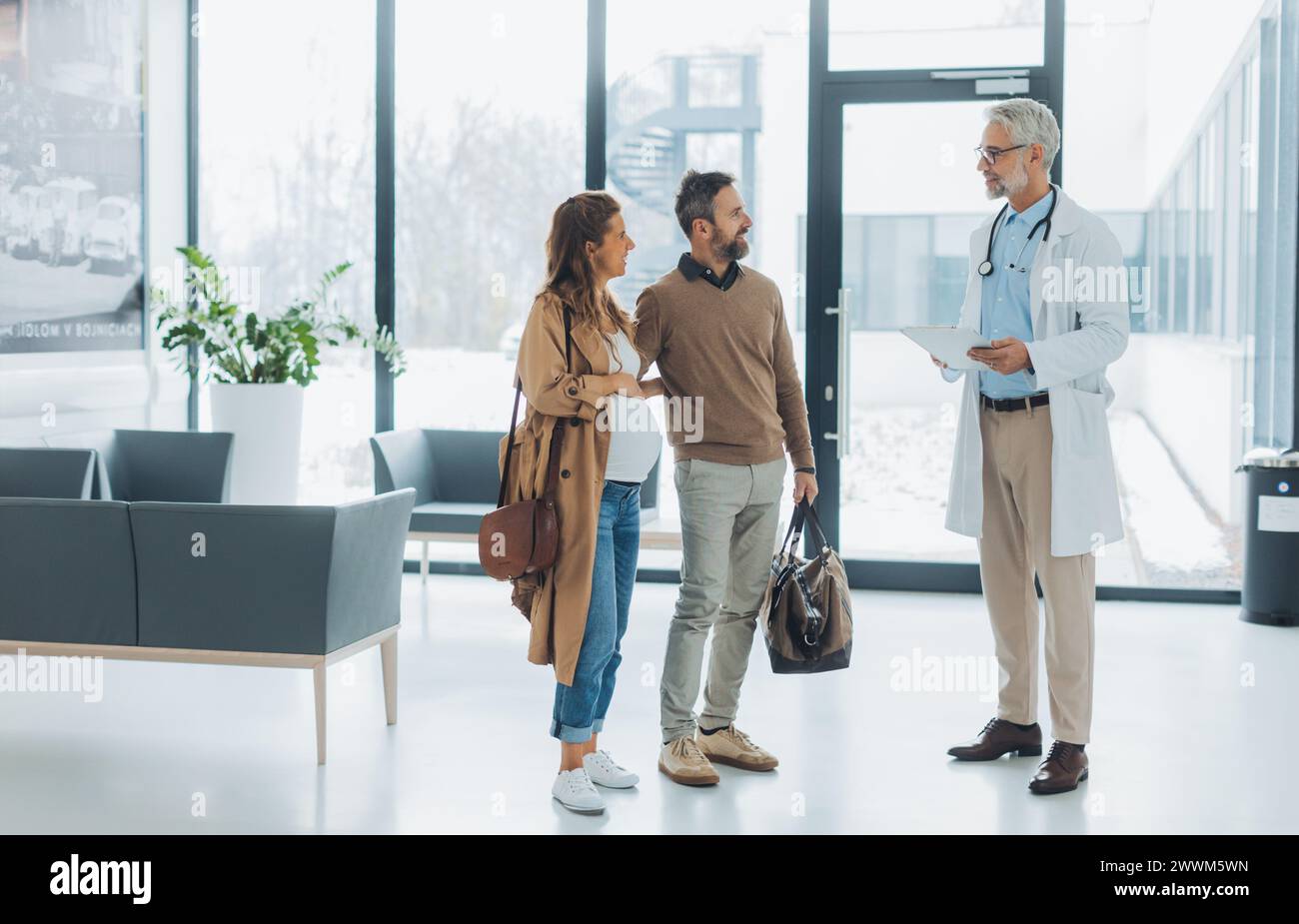 Pregnant woman and husband talking to obstetrician in hospital ...