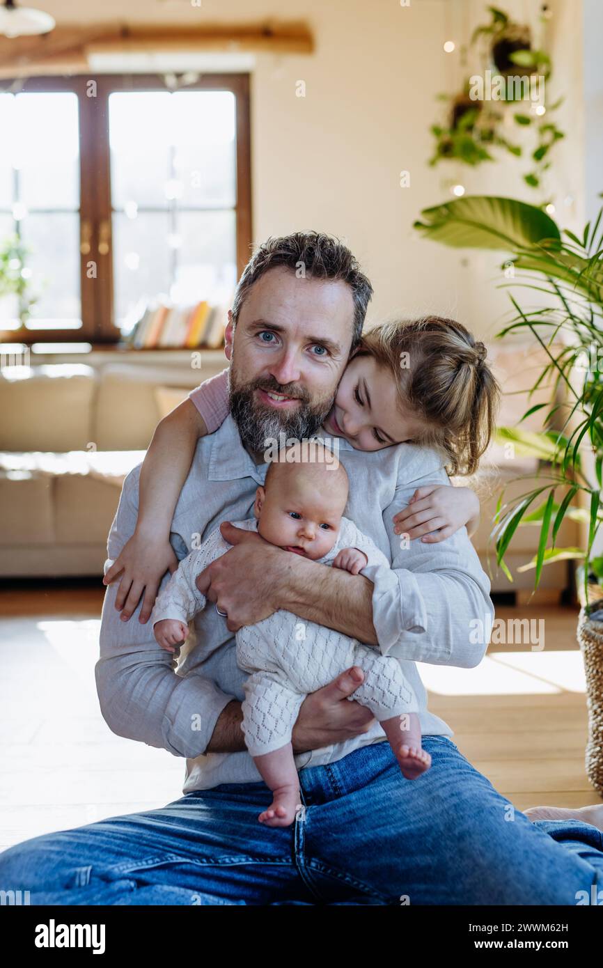 Father holding newborn baby girl, older daughter with them. New sibling ...