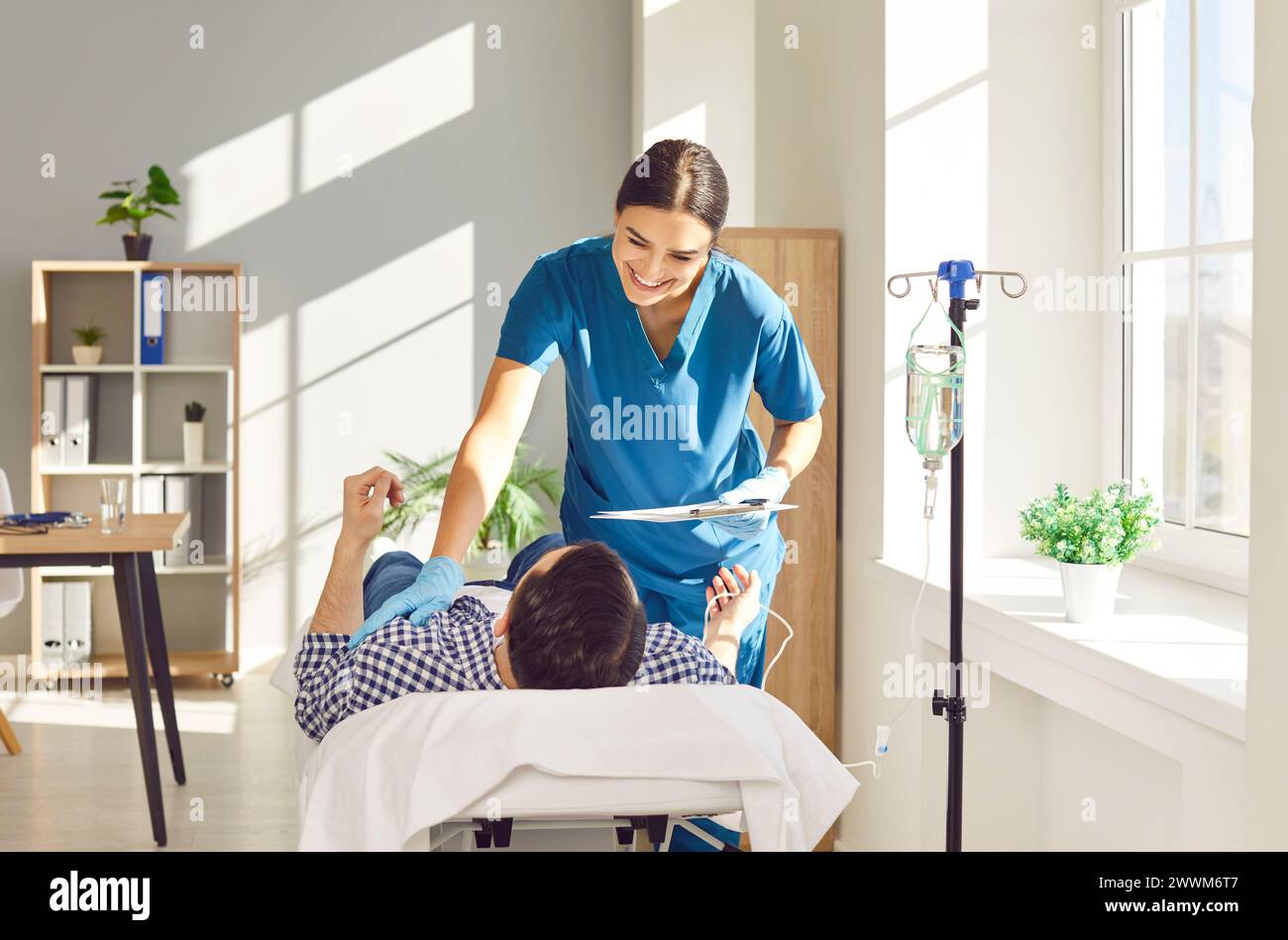 Nurse supporting and giving consultation to patient receiving IV drip ...