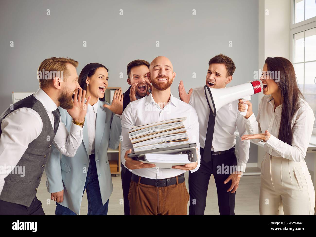 Man holding a pile of documents in office with a group of noisy ...