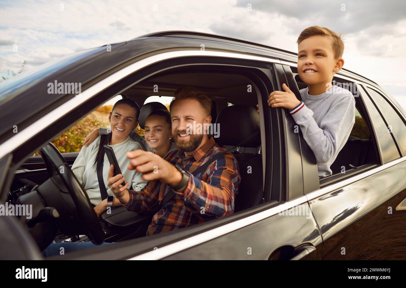 Happy family sitting inside car using digital map application and ...