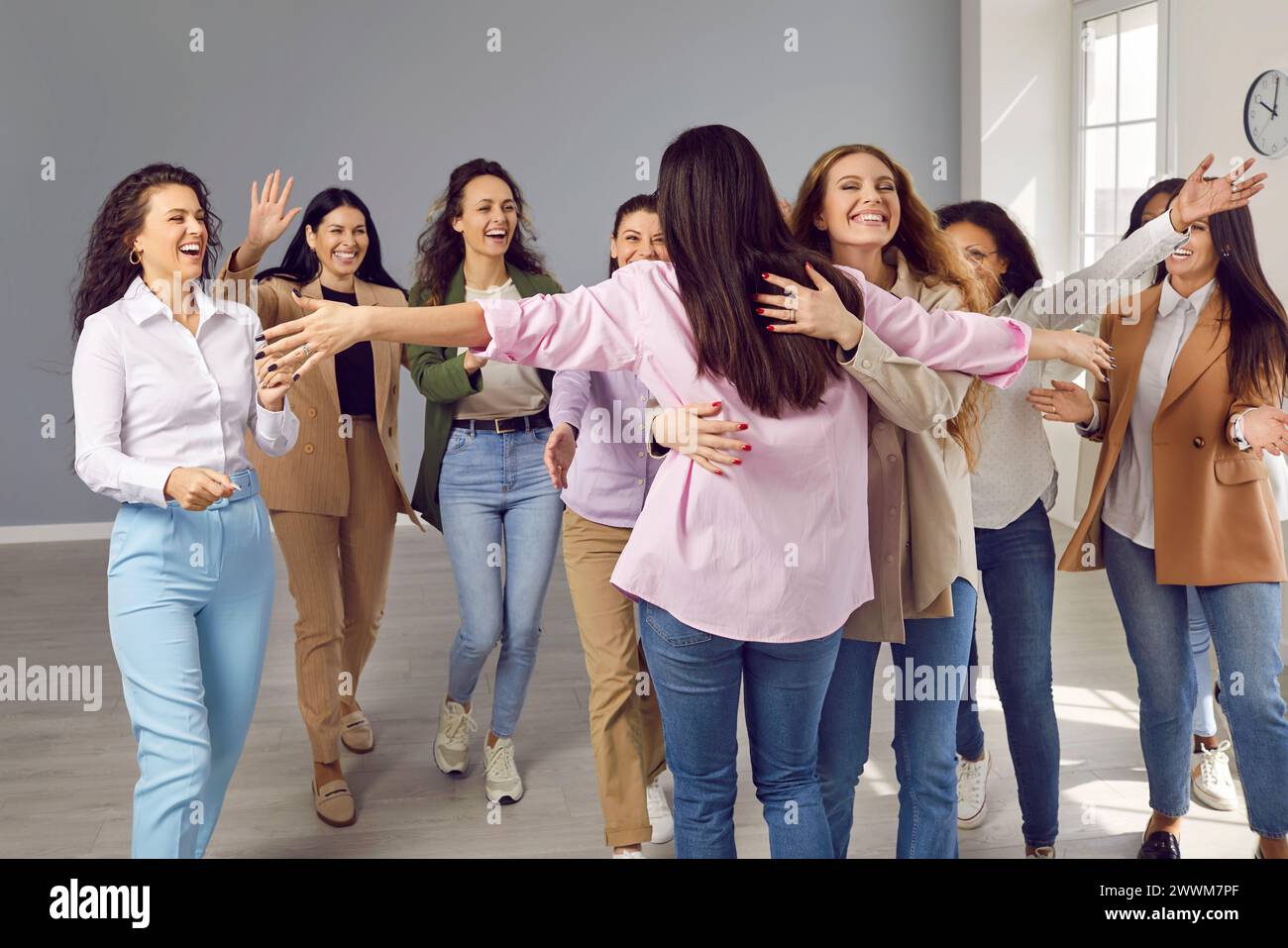 Team of happy business women hugging their friend who they haven't seen ...