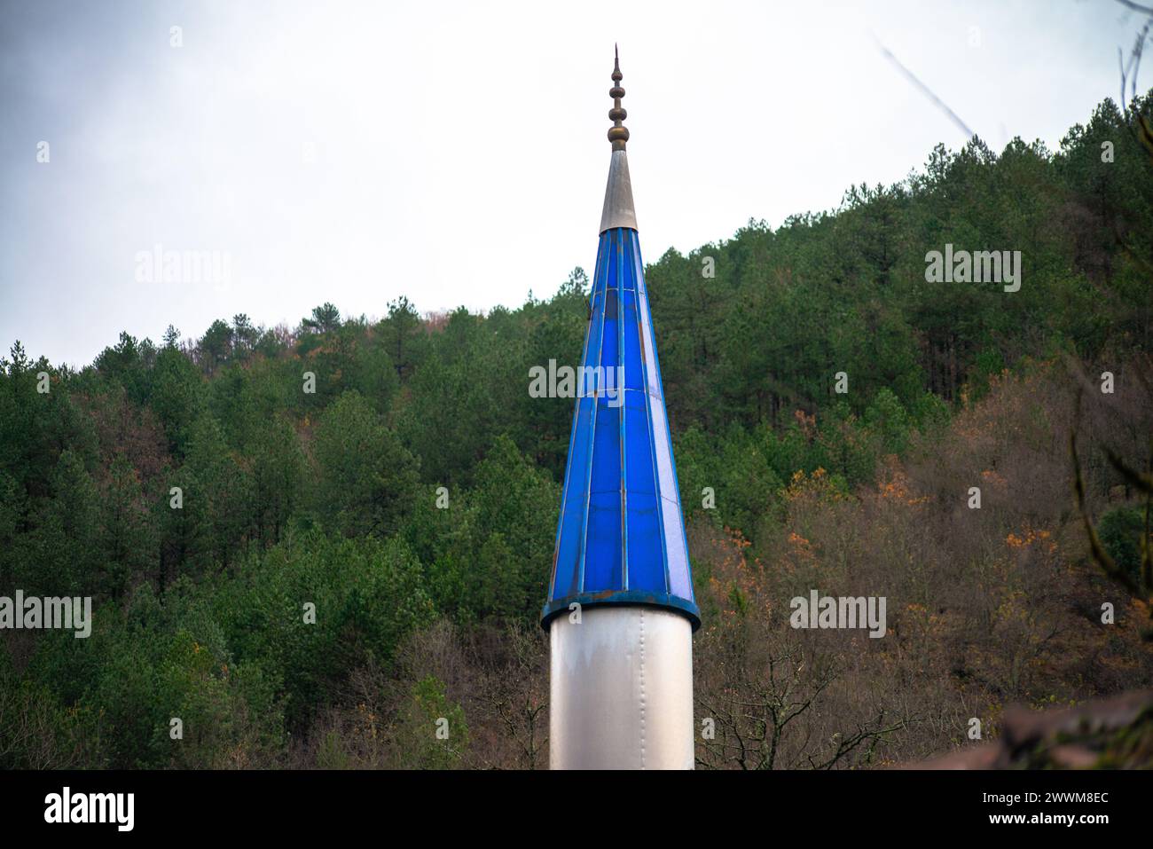 The slender tip of a blue minaret reaches towards the sky, adorned with ...